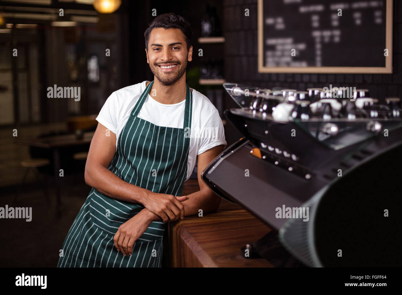 Smiling barista leaning against counter Stock Photo - Alamy