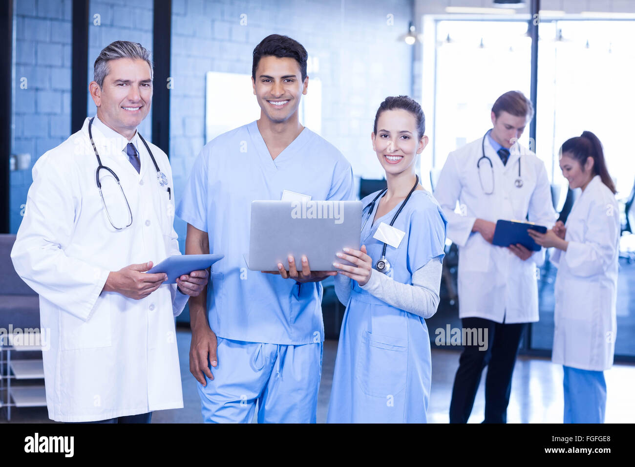 Doctors using laptop and digital tablet looking at camera Stock Photo ...