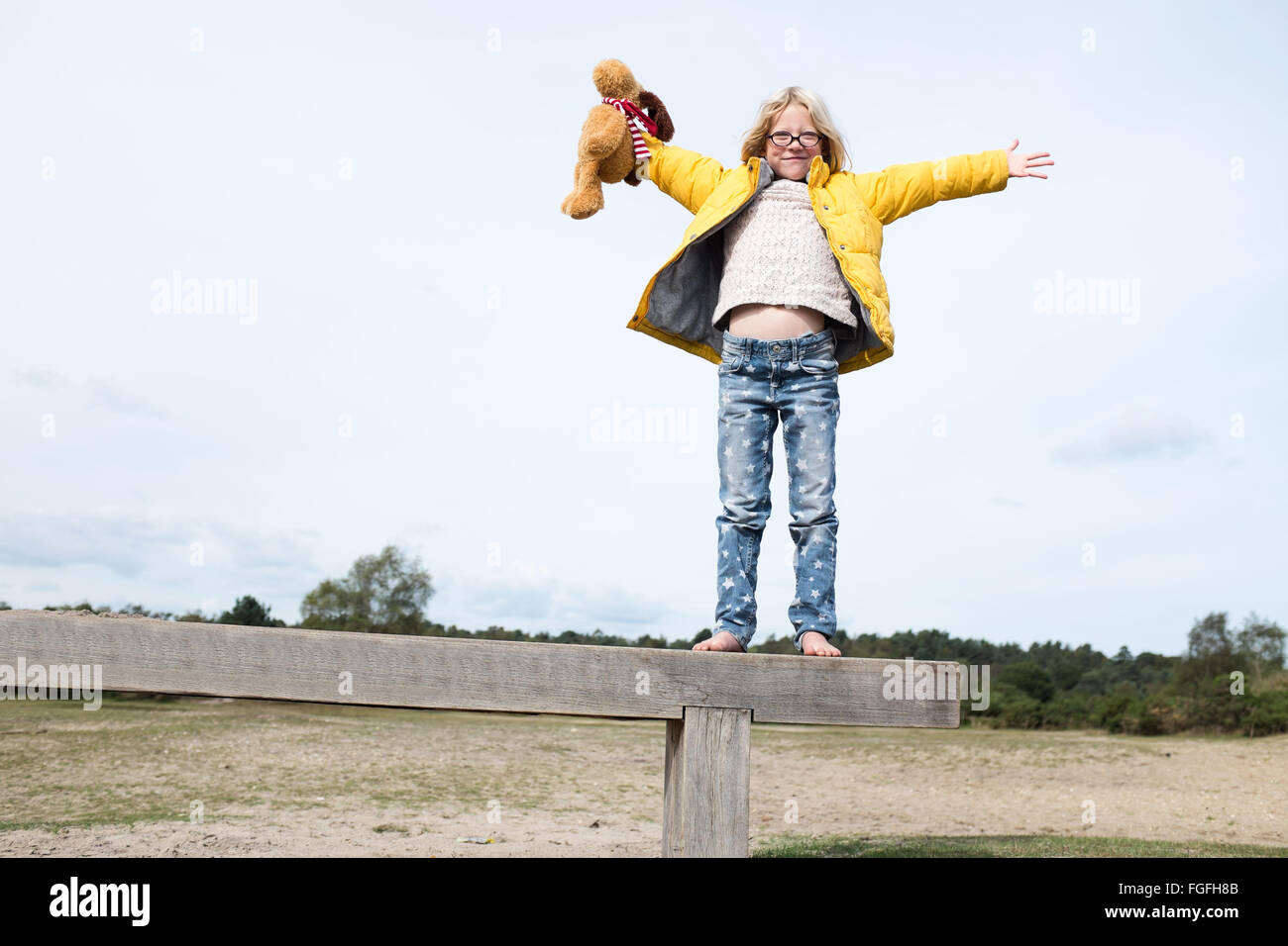 Little girl with arms in air with teddy on a bench Stock Photo - Alamy