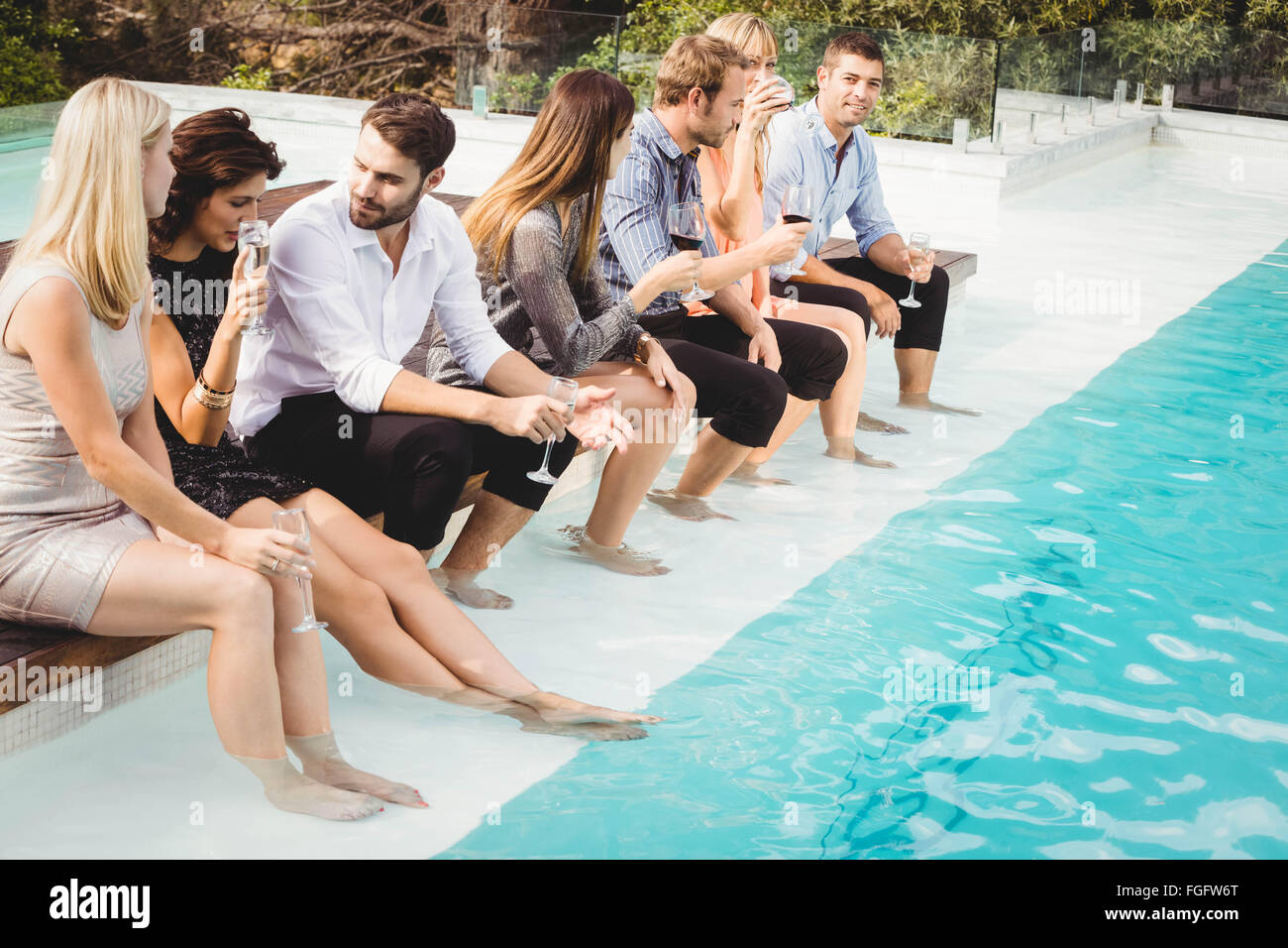 Young people sitting by swimming pool Stock Photo - Alamy