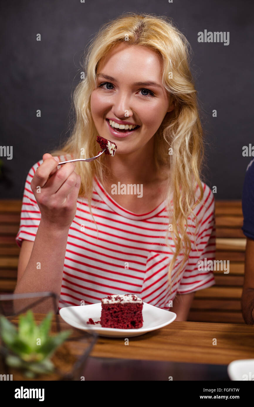Smiling blonde enjoying a pastry Stock Photo - Alamy