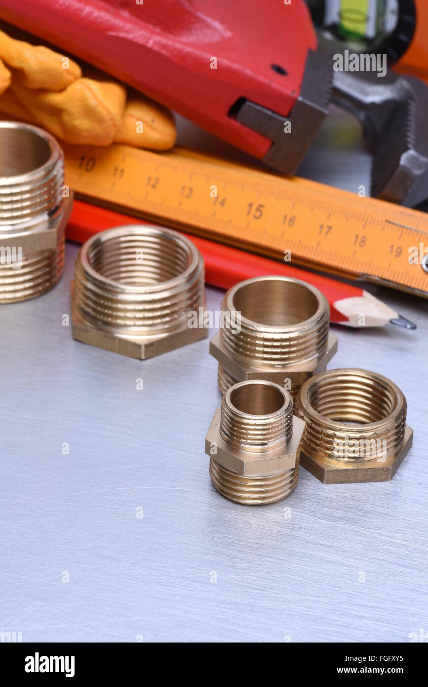 Parts of plumbing fitting with wrench and tools on metal surface Stock ...