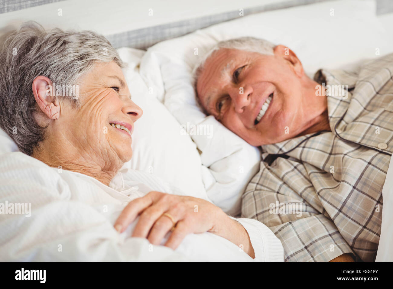 Happy senior couple smiling in bed Stock Photo - Alamy