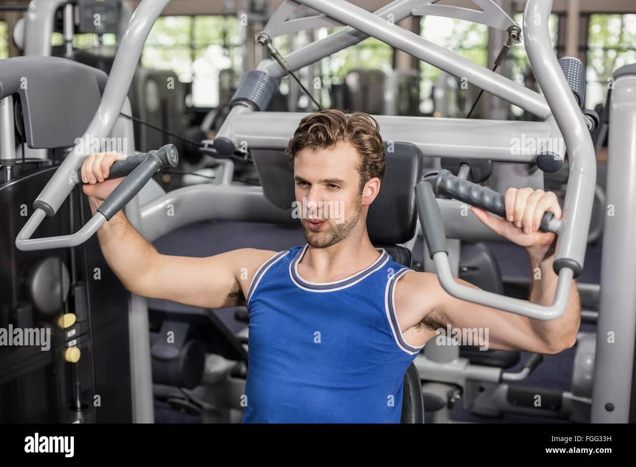 Fit man using weight machine Stock Photo - Alamy