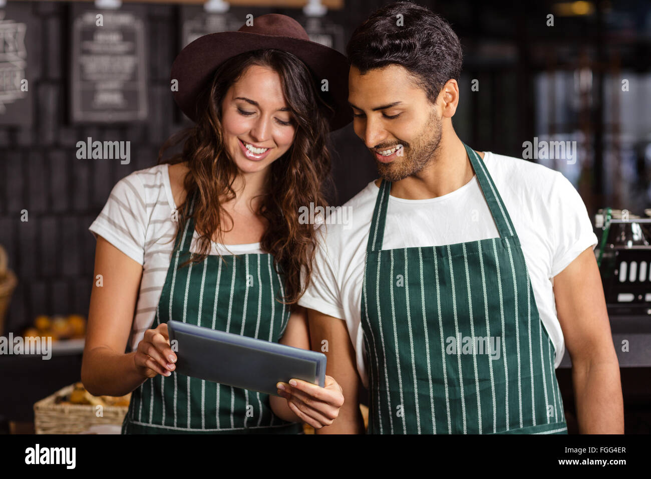 Smiling baristas using tablet Stock Photo - Alamy