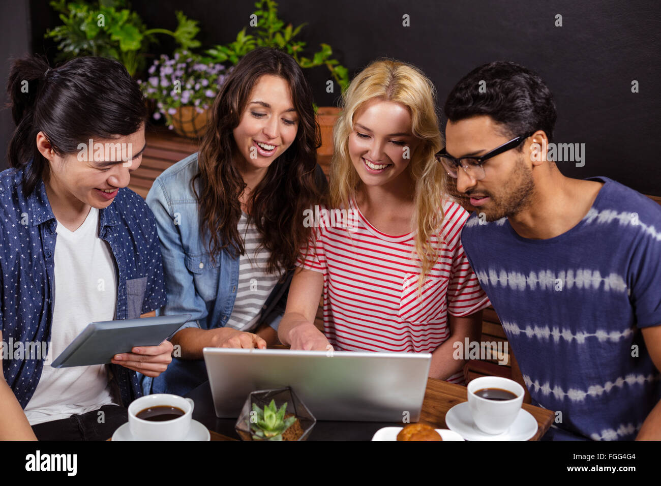 Smiling friends enjoying coffee together and using technologies Stock ...