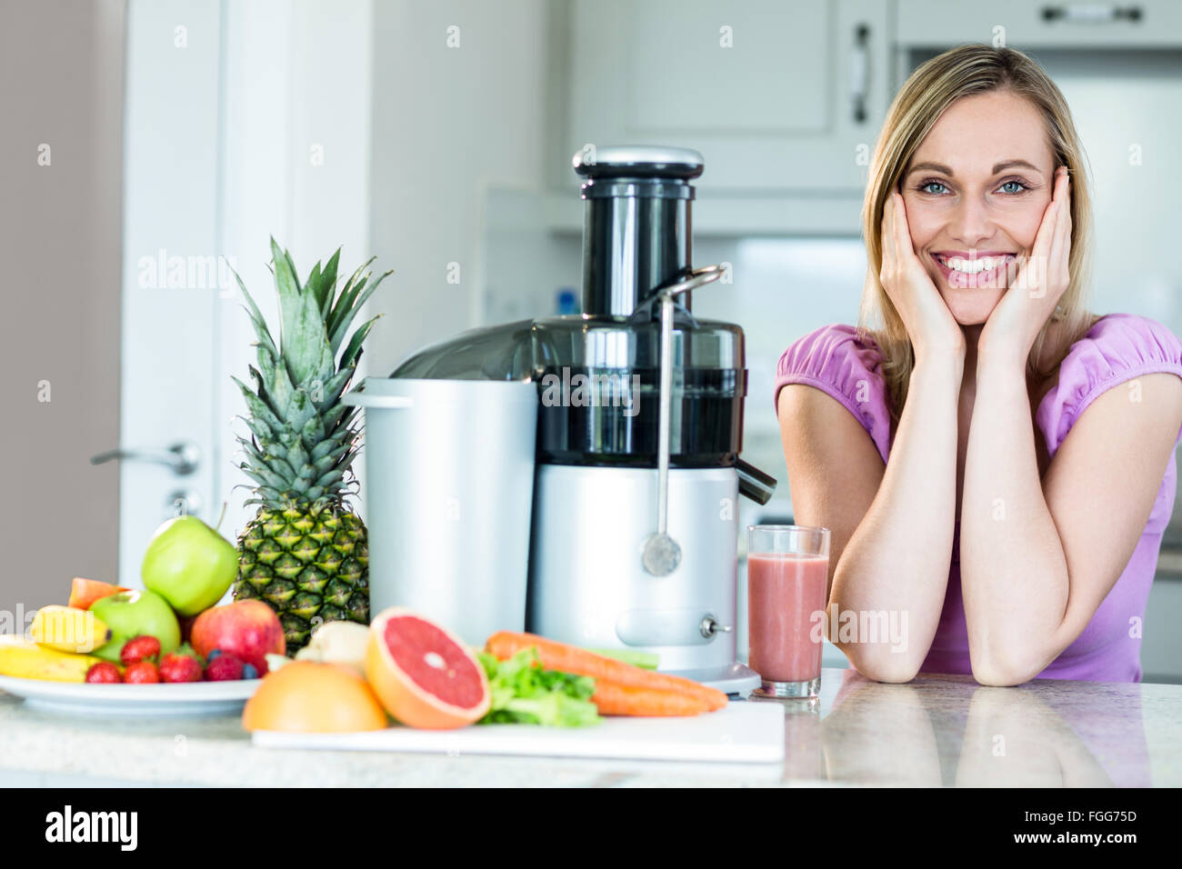 Blonde woman drinking a smoothie in the kitchen Stock Photo - Alamy