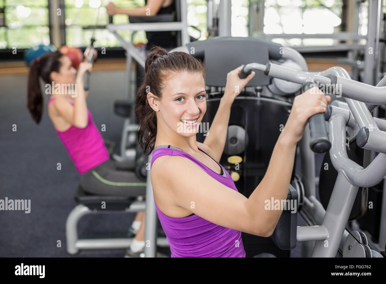 Fit woman using weight machine Stock Photo - Alamy