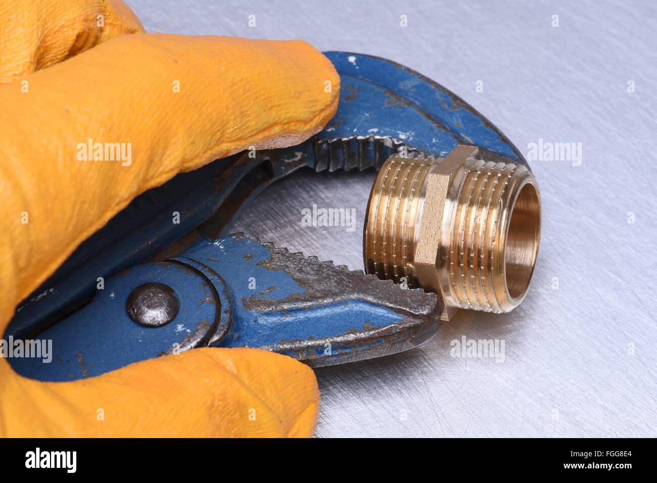Hand in glove holding wrench and fitting brass part Stock Photo - Alamy