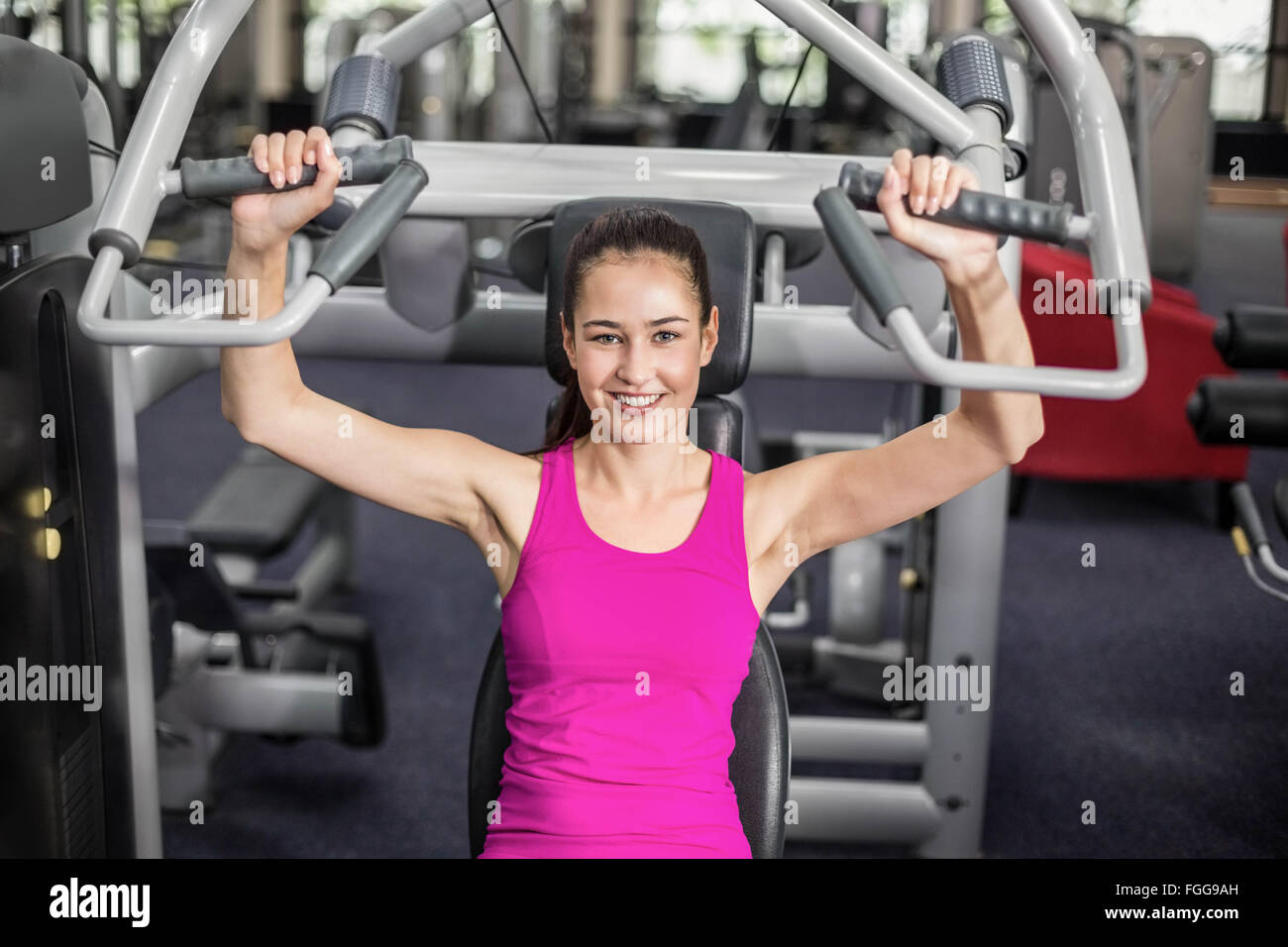 Fit woman using weight machine Stock Photo - Alamy