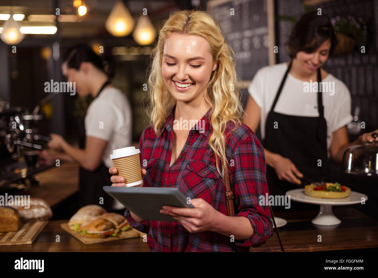 Smiling blonde customer in front of the counter using tablet Stock ...