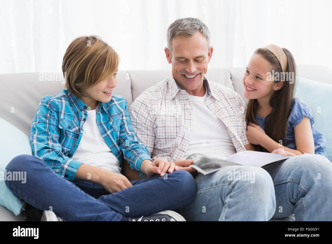 Happy family on the couch reading storybook Stock Photo - Alamy