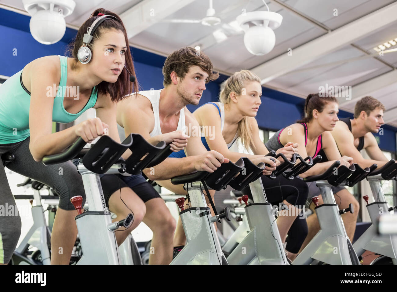 Fit group of people using exercise bike together Stock Photo - Alamy