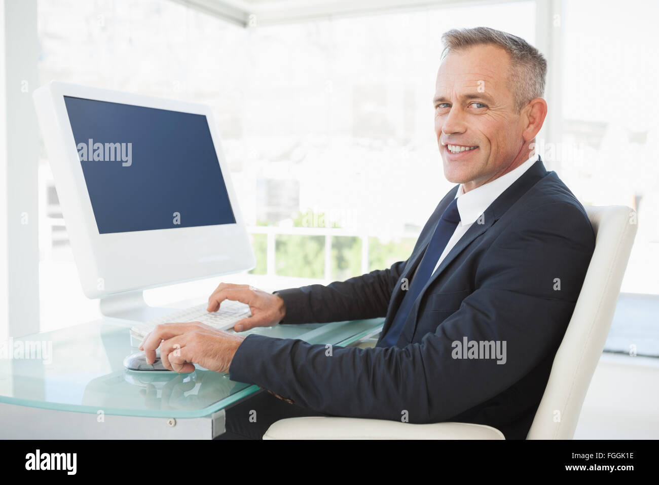 A smiling businessman uses his computer Stock Photo - Alamy