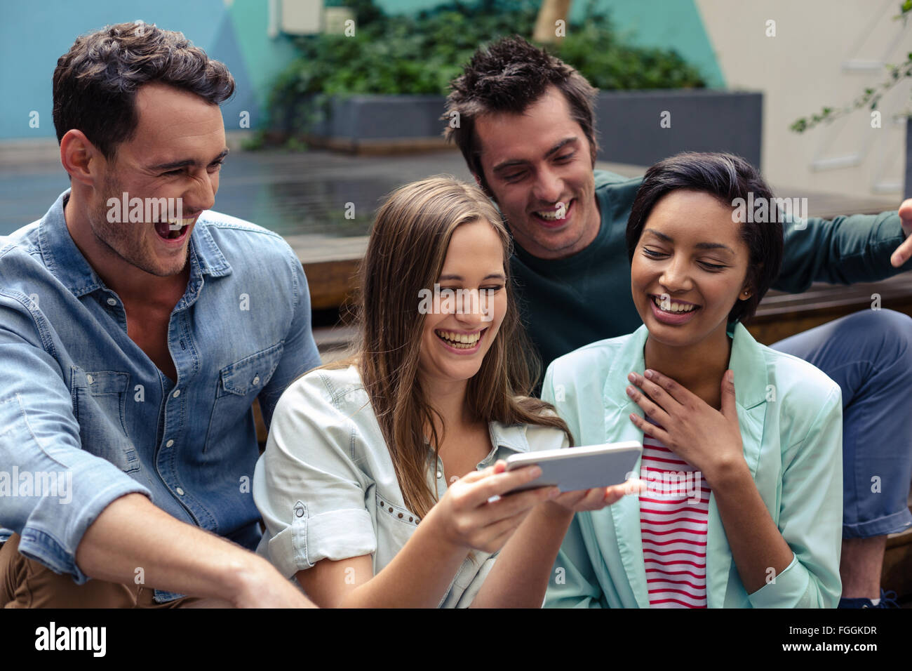 Happy friends using smartphone Stock Photo - Alamy