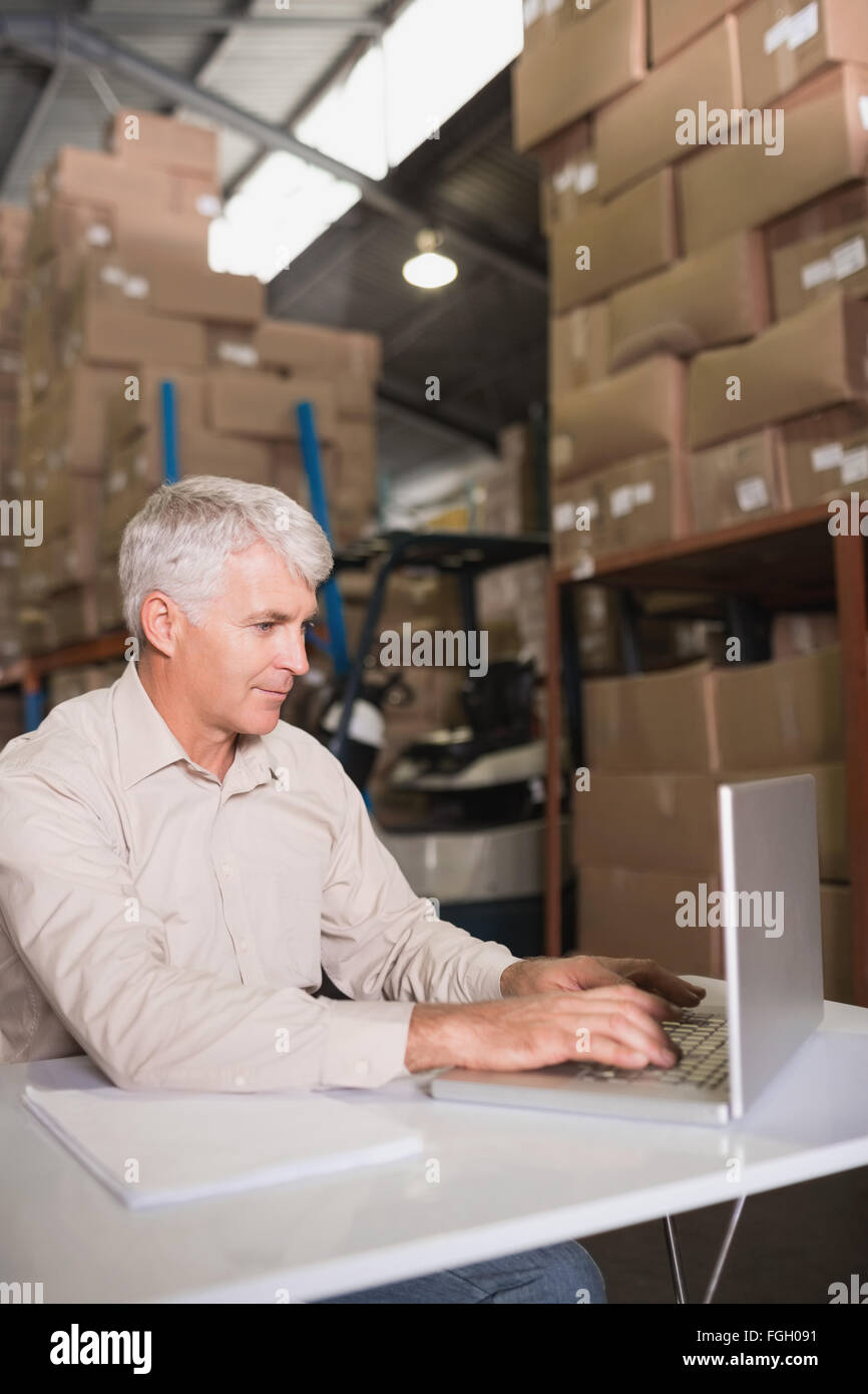 Concentrated warehouse manager using laptop Stock Photo - Alamy