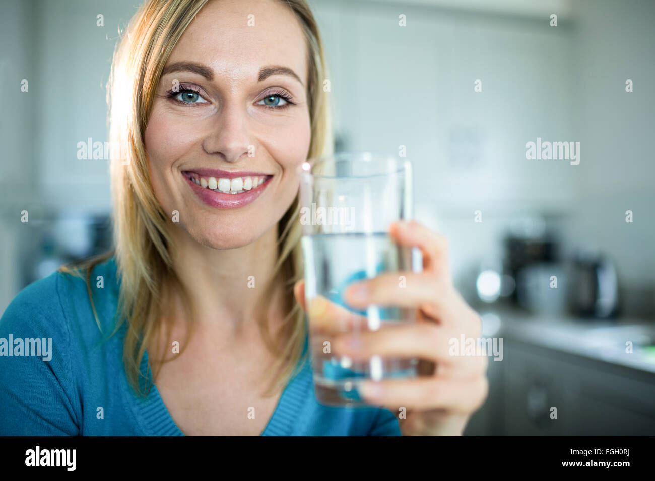 Pretty blonde woman drinking a glass of water Stock Photo - Alamy