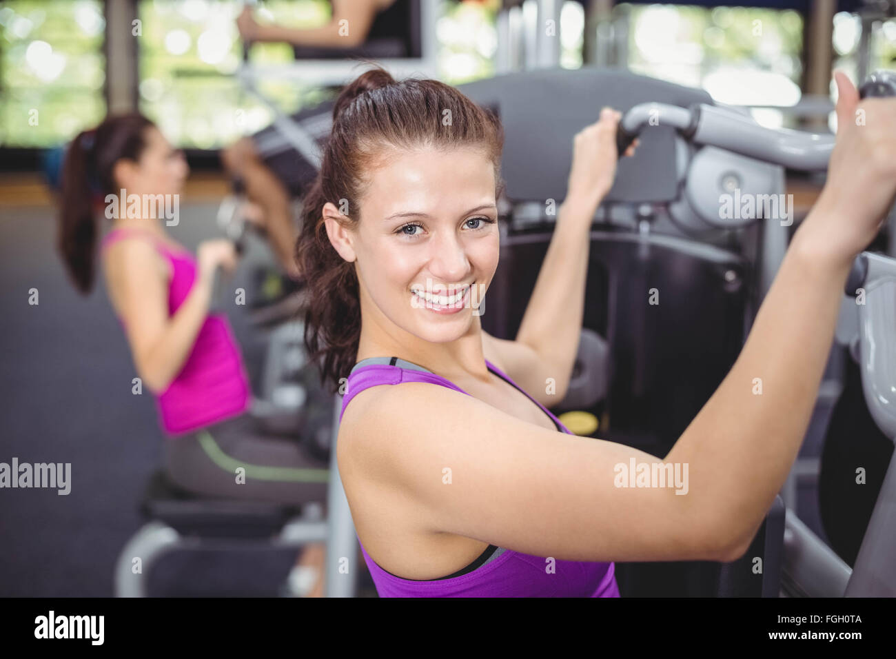 Fit woman using weight machine Stock Photo - Alamy