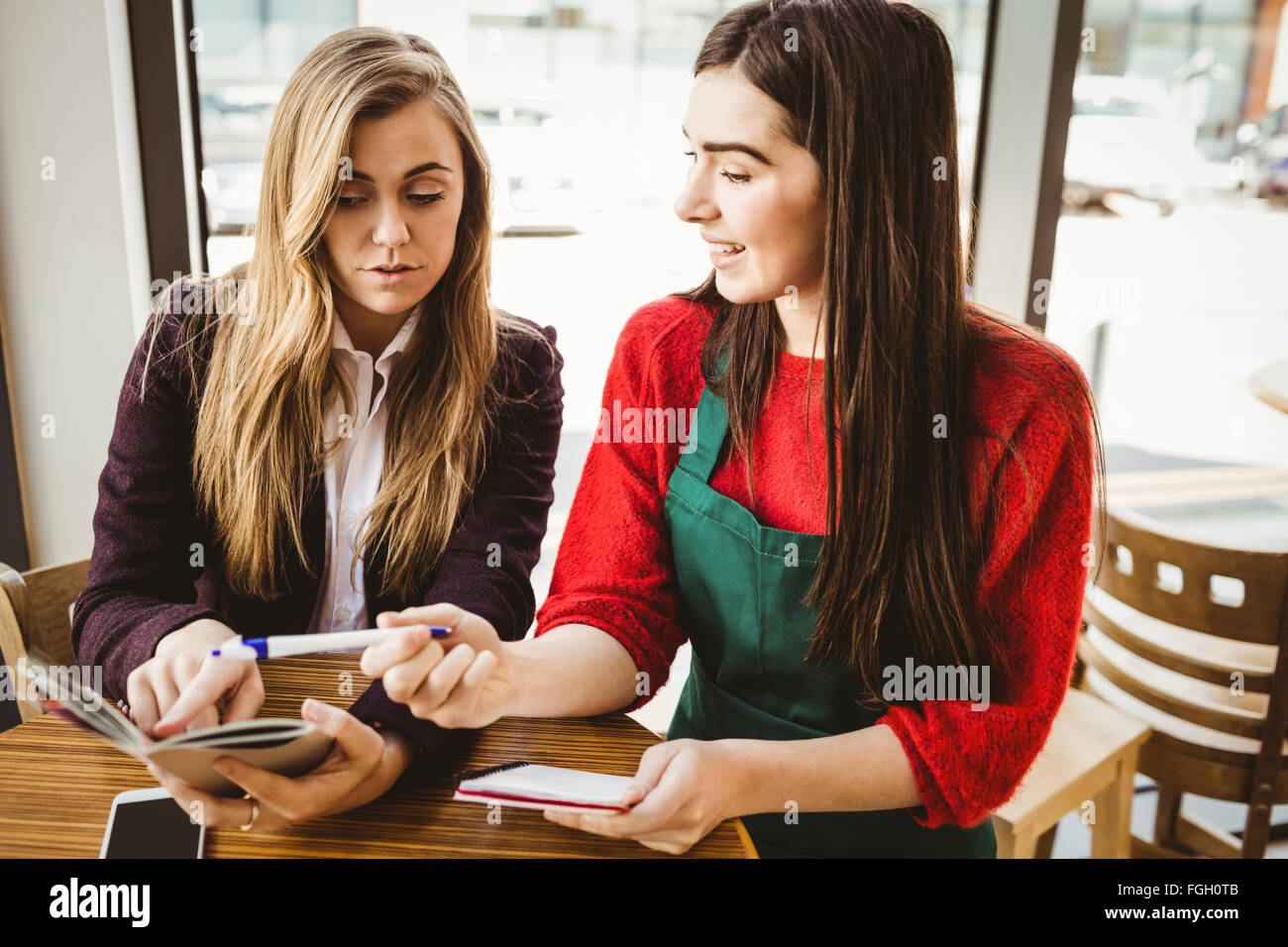 Cute blonde girl ordering from her friend Stock Photo - Alamy