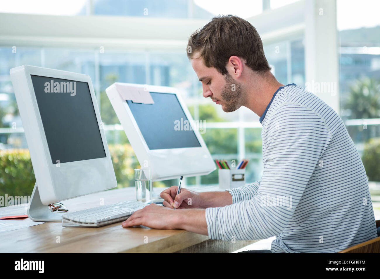 Handsome man working on computer and taking notes Stock Photo - Alamy