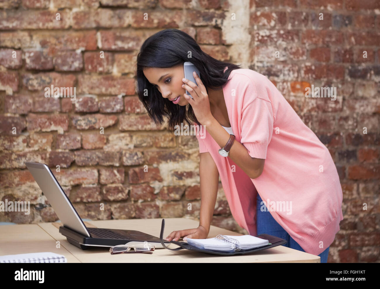 Woman calling with her mobile phone and looking at diary Stock Photo ...