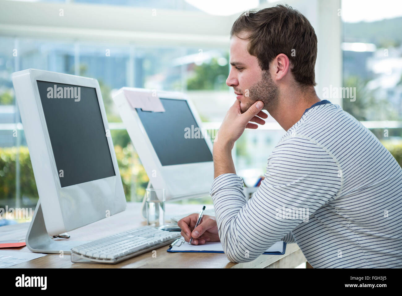 Handsome man working on computer and taking notes Stock Photo - Alamy