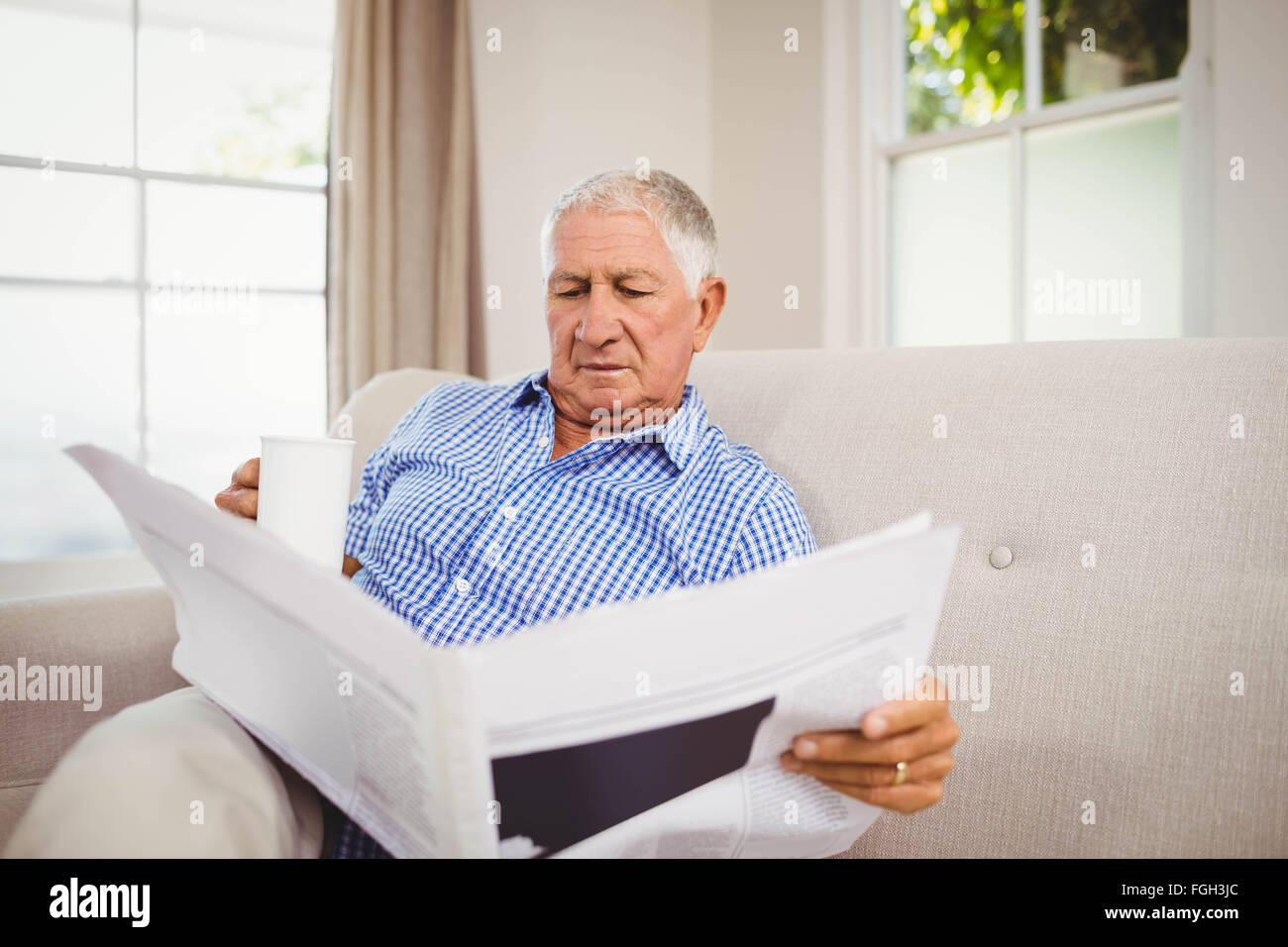 Senior man reading newspaper in living room Stock Photo - Alamy