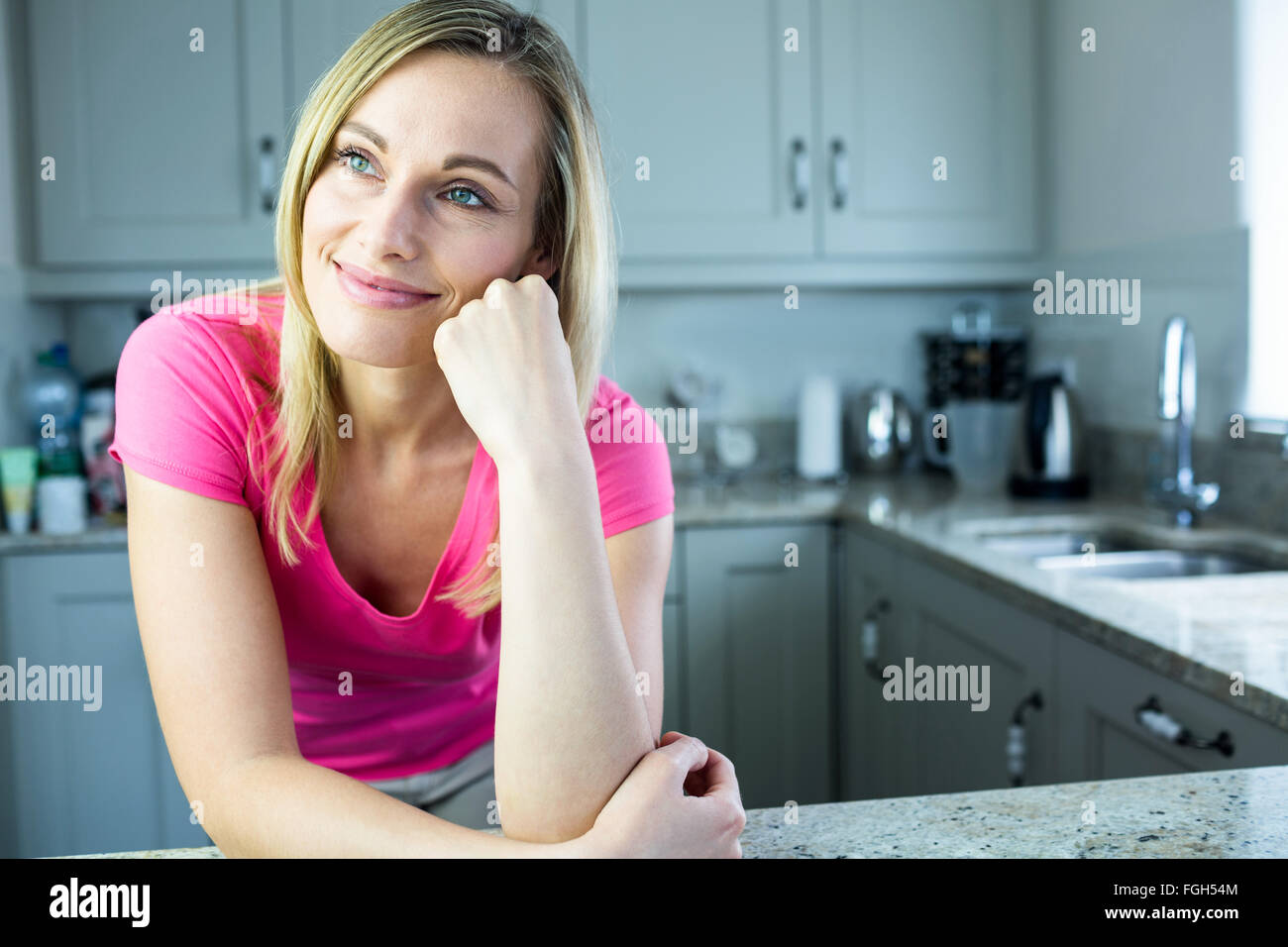 Pretty blonde woman leaning on the counter Stock Photo - Alamy