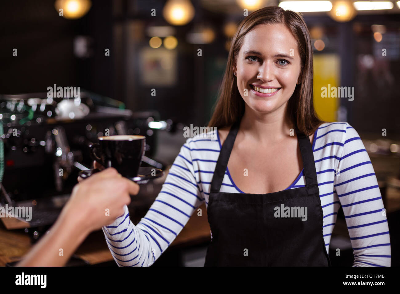 Pretty barista giving coffee to customer and smiling at the camera ...
