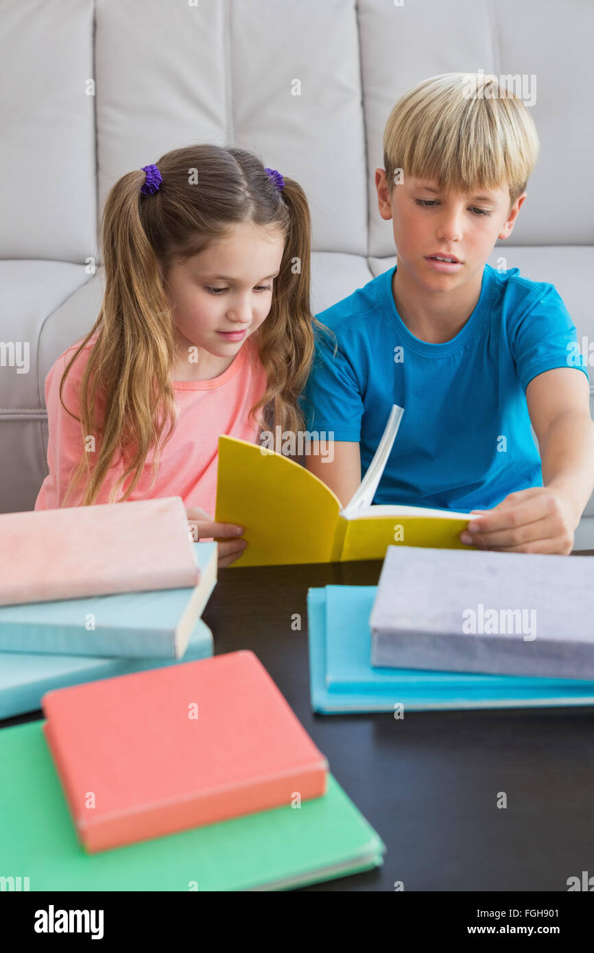 Happy siblings reading books on floor Stock Photo - Alamy