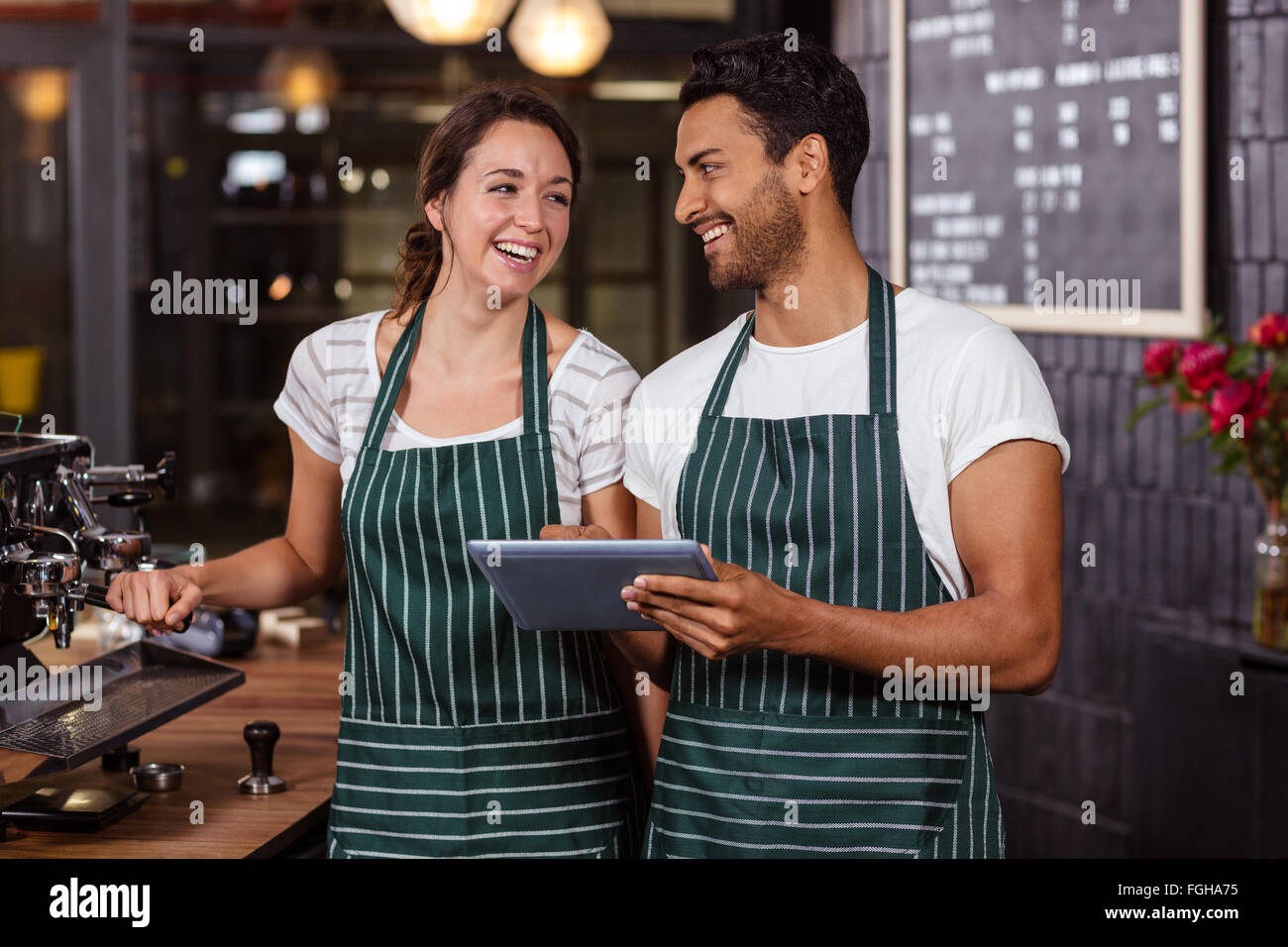 Smiling baristas using tablet Stock Photo - Alamy