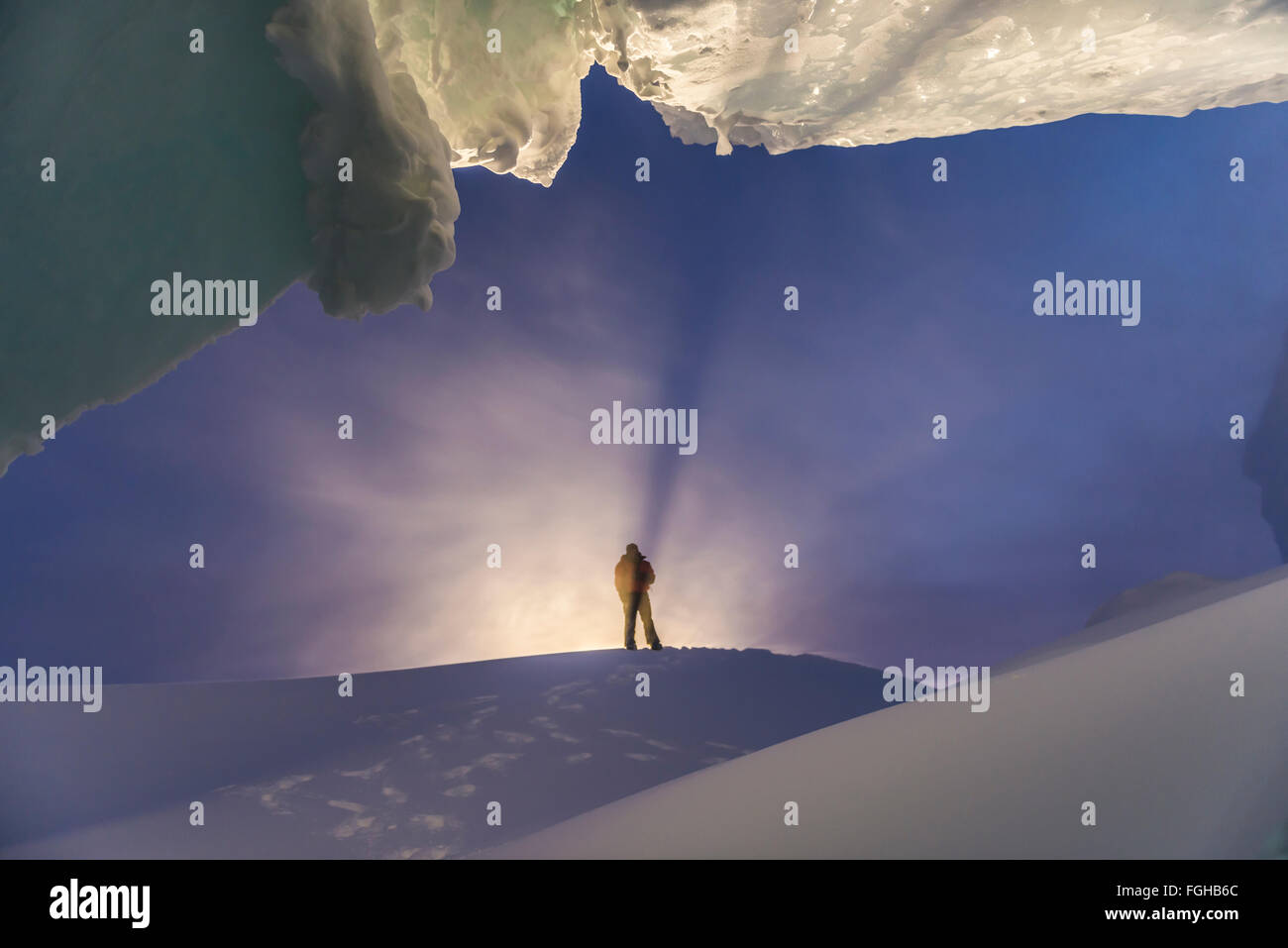 A man stands at the entrance of an ice cave during a winter visit to ...
