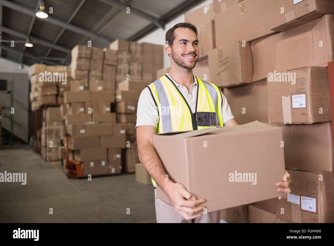 Worker carrying box in warehouse Stock Photo - Alamy
