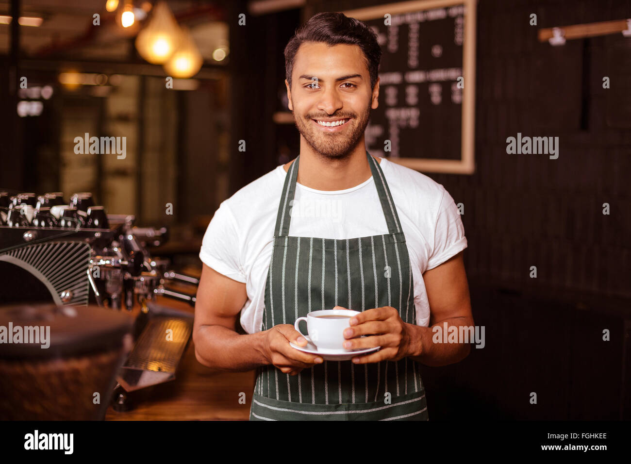 Smiling barista holding coffee Stock Photo - Alamy