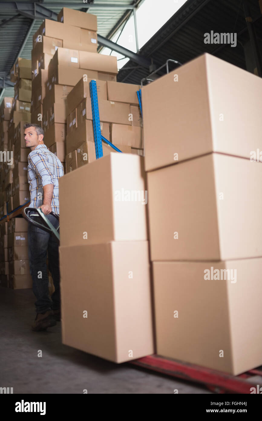 Worker pulling trolley with boxes in warehouse Stock Photo - Alamy
