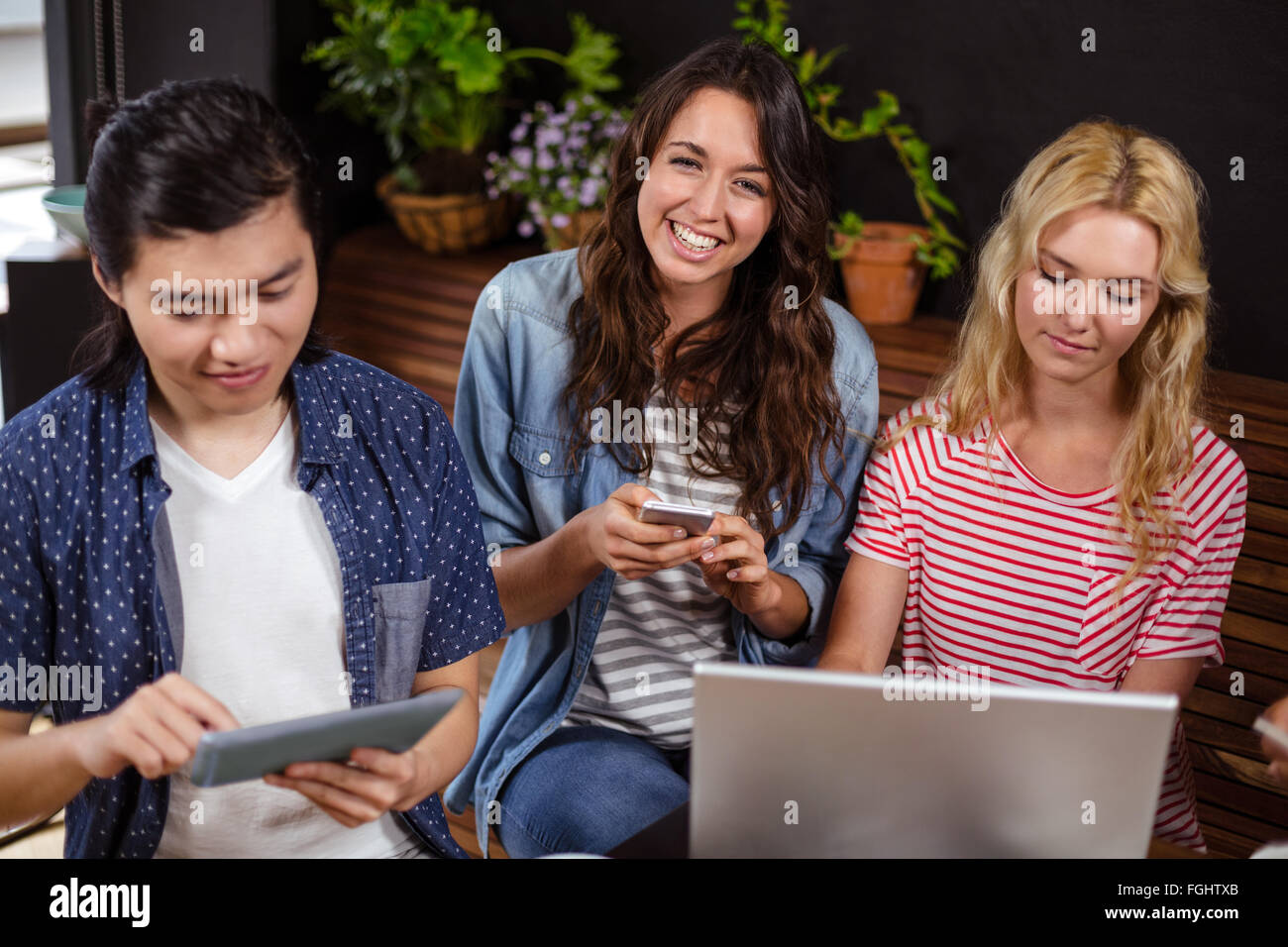 Smiling friends enjoying coffee together and using technologies Stock ...