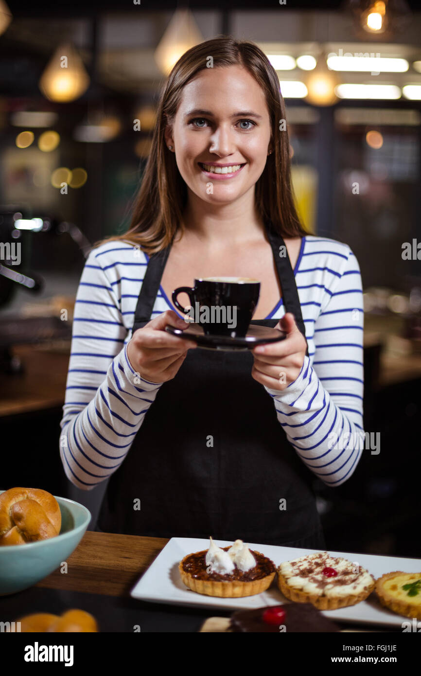 Smiling barista holding coffee Stock Photo - Alamy