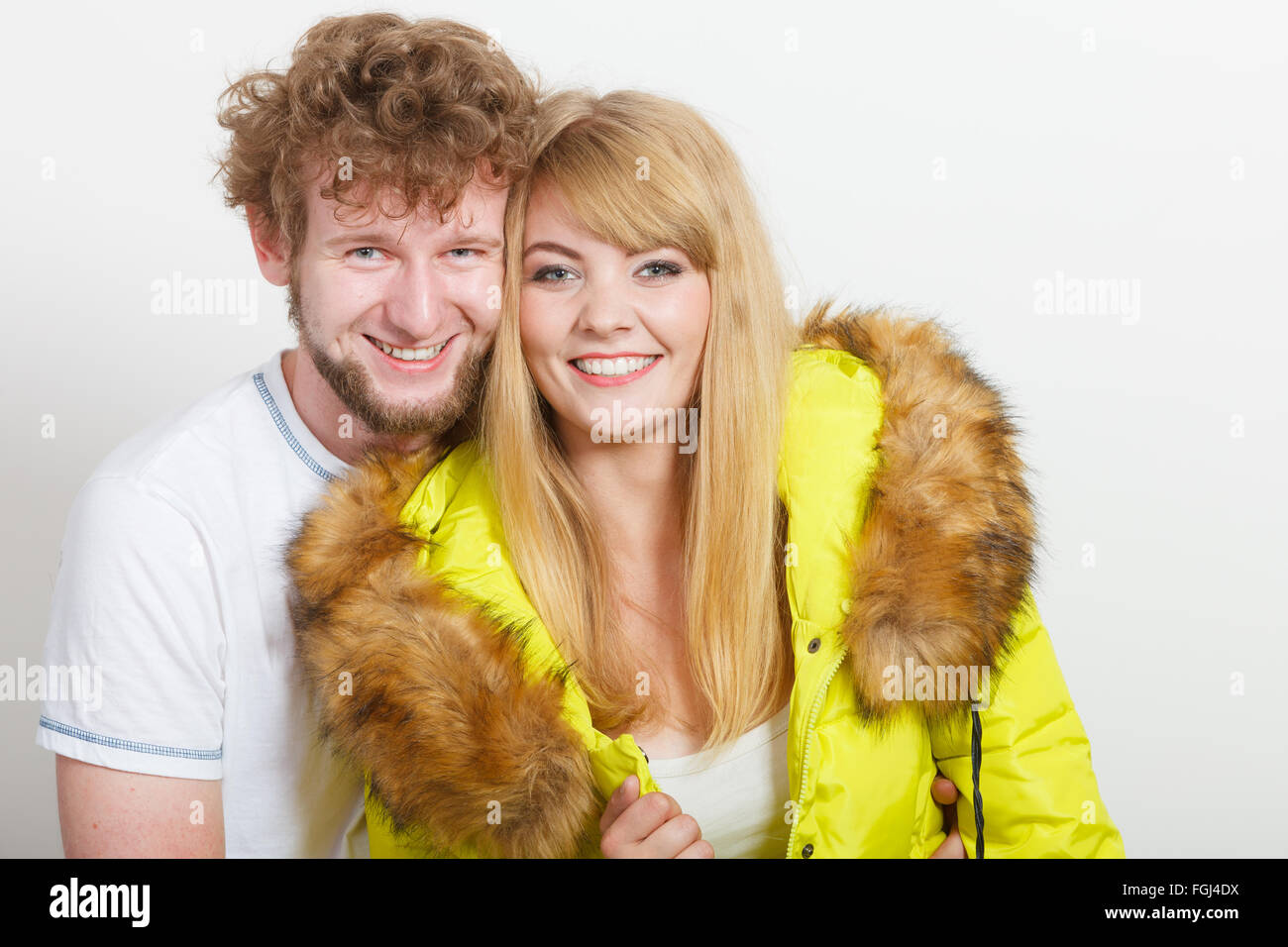 Happy joyful couple posing in studio. Young woman in warm lime jacket ...