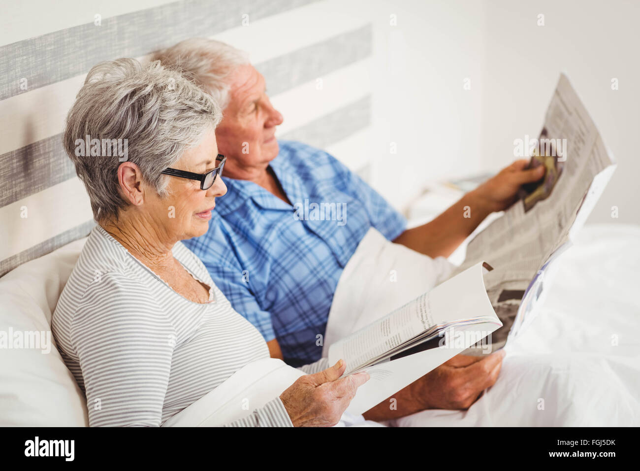 Senior woman reading magazine and senior man reading newspaper Stock ...