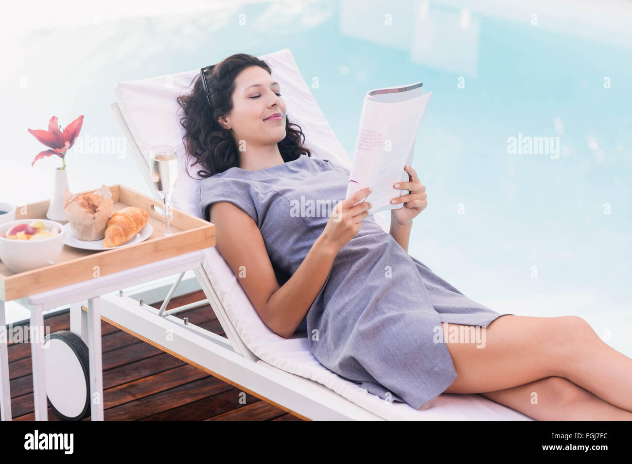 Young woman reading magazine near poolside Stock Photo - Alamy