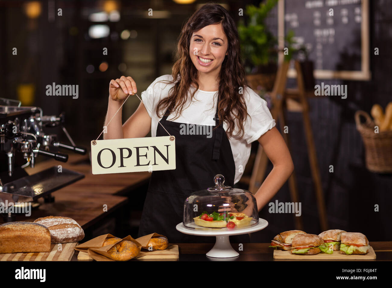 Pretty waitress holding a open sign Stock Photo - Alamy