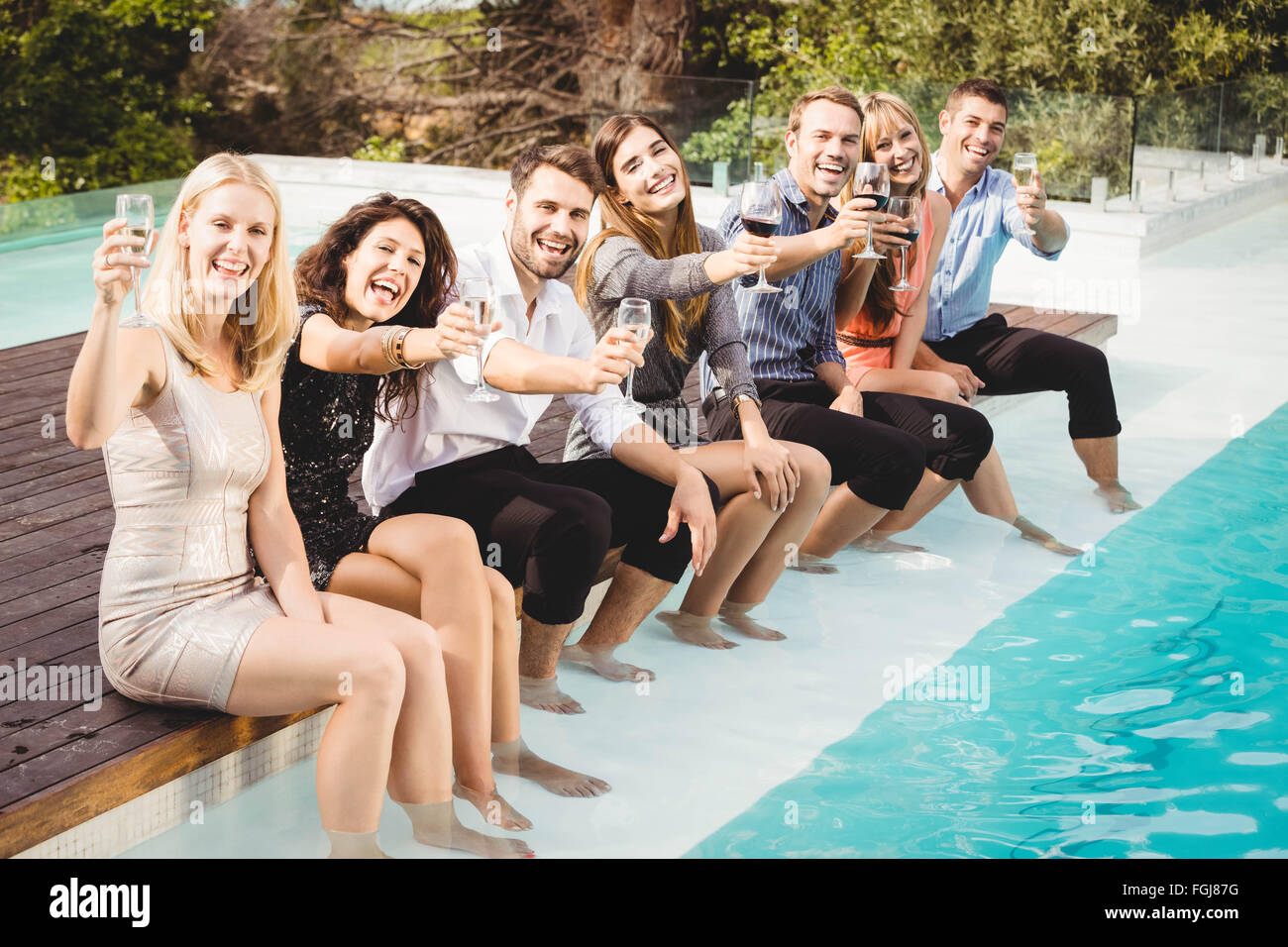 Young people sitting by swimming pool Stock Photo - Alamy