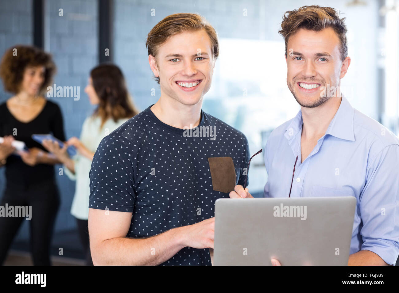 Portrait of men holding a laptop and smiling Stock Photo - Alamy