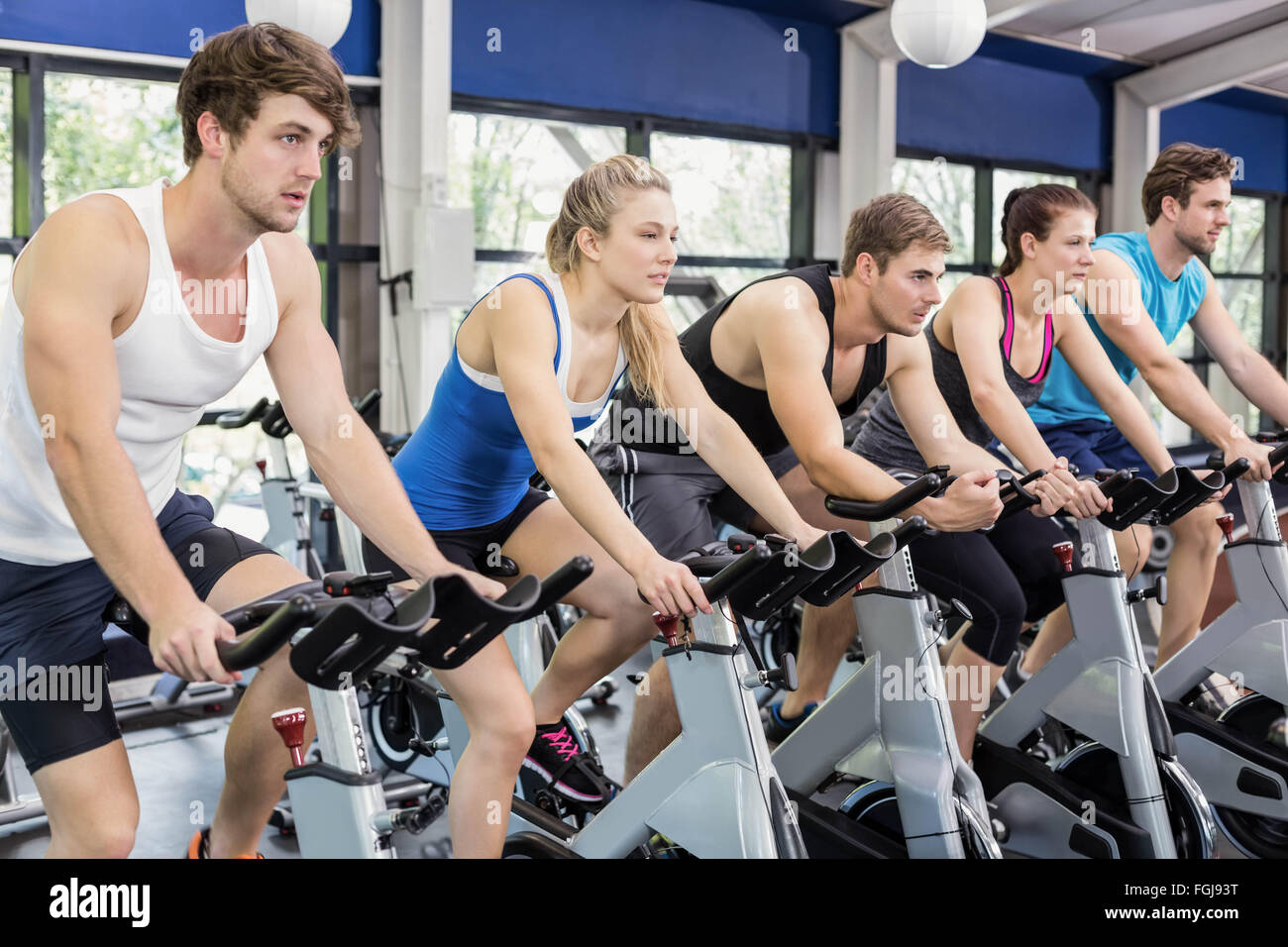 Fit group of people using exercise bike together Stock Photo - Alamy