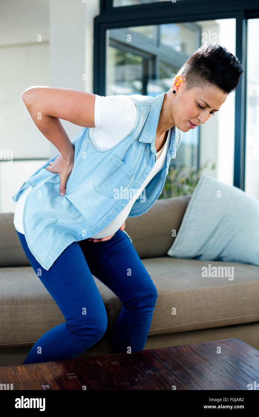 Pregnant woman bending forward with hand on hip Stock Photo - Alamy