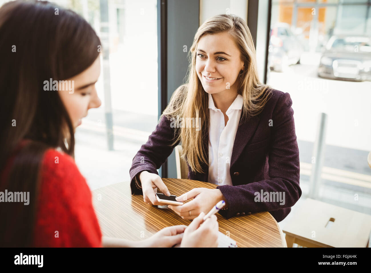 Cute blonde girl ordering from her friend Stock Photo - Alamy