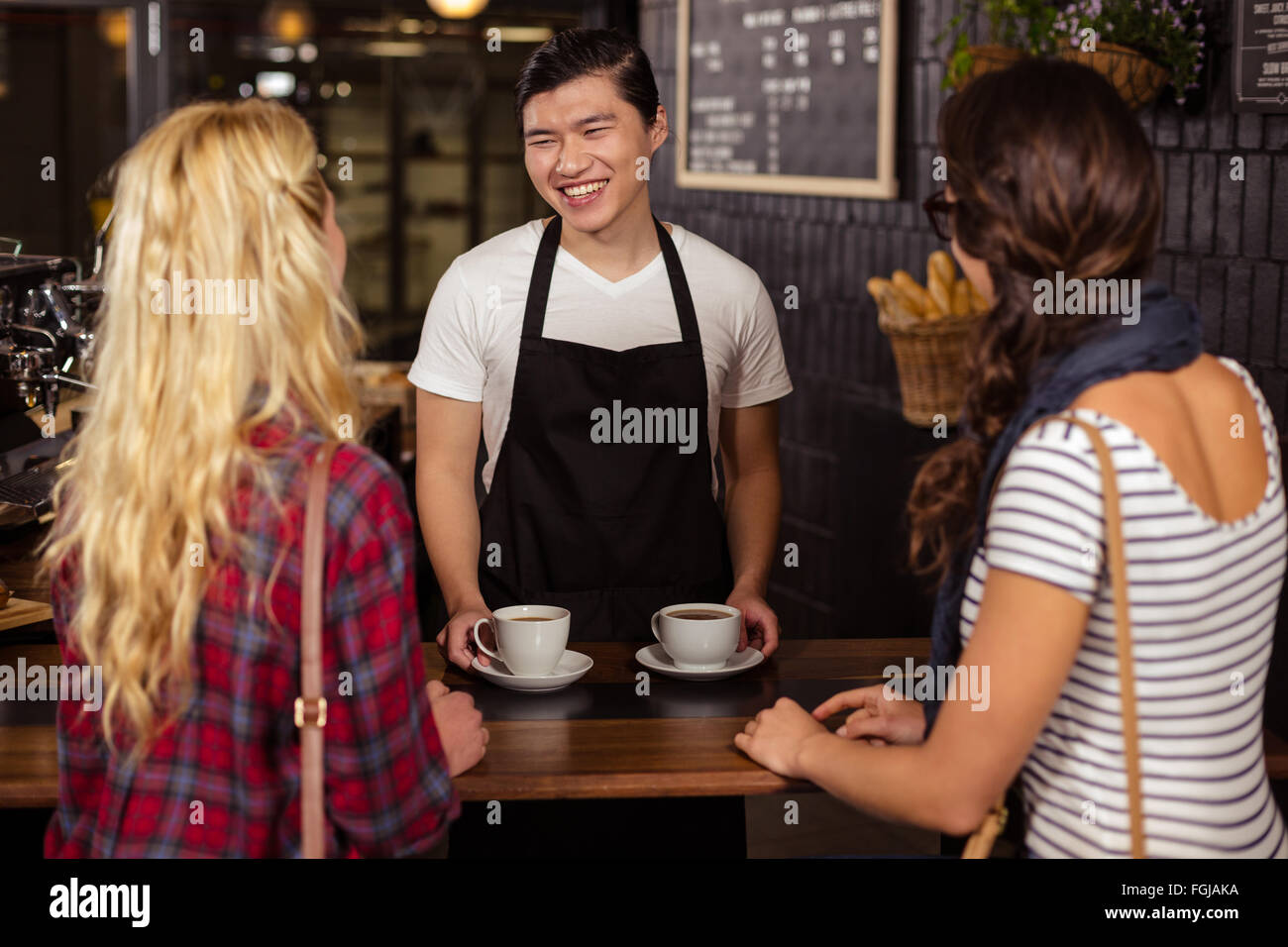 Smiling waiter serving a coffee to customers Stock Photo - Alamy
