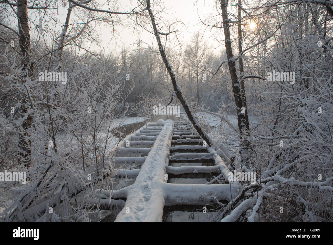 Old broken wooden pedestrian bridge covered with snow in winter Stock ...