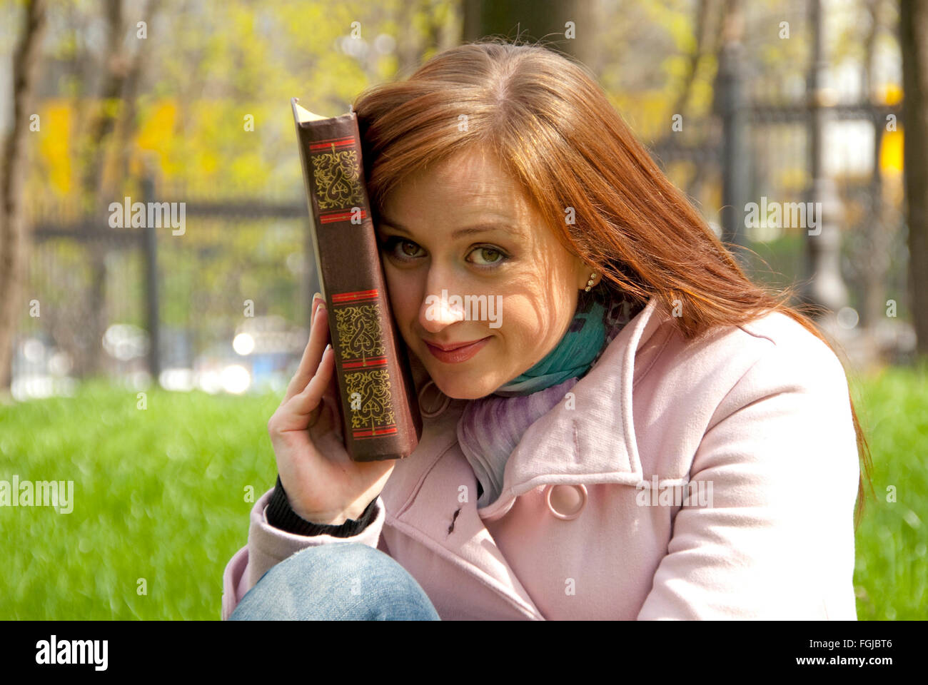 Beautiful redhead woman reading book on a meadow Stock Photo - Alamy
