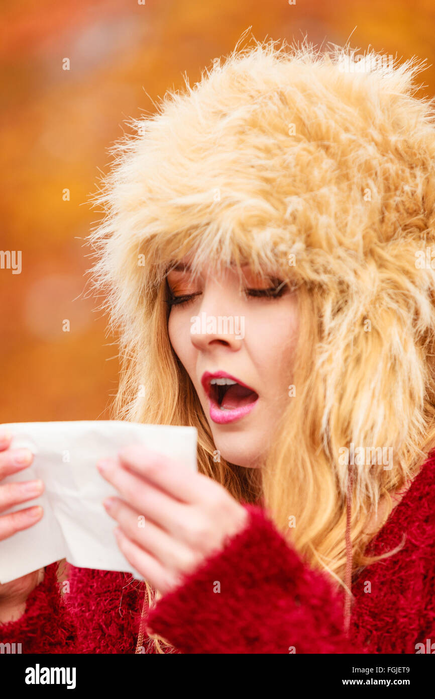 Sick ill young woman girl in fall autumn forest park sneezing into ...